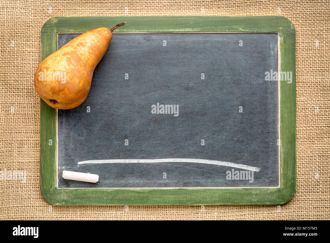 blank slate blackboard with a pear and white chalk against burlap ...