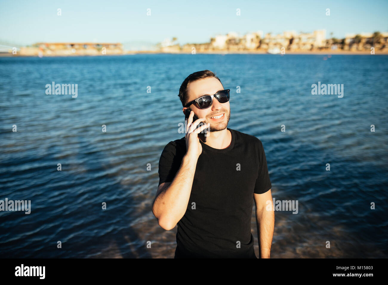 young man talking with mobile phone on the beach Stock Photo - Alamy