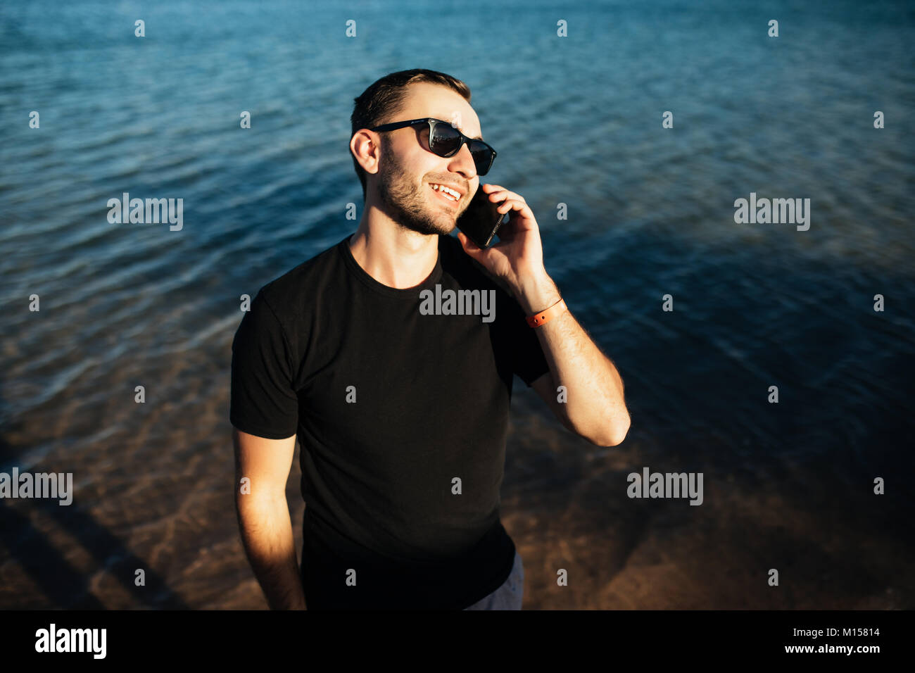 young man talking with mobile phone on the beach Stock Photo - Alamy