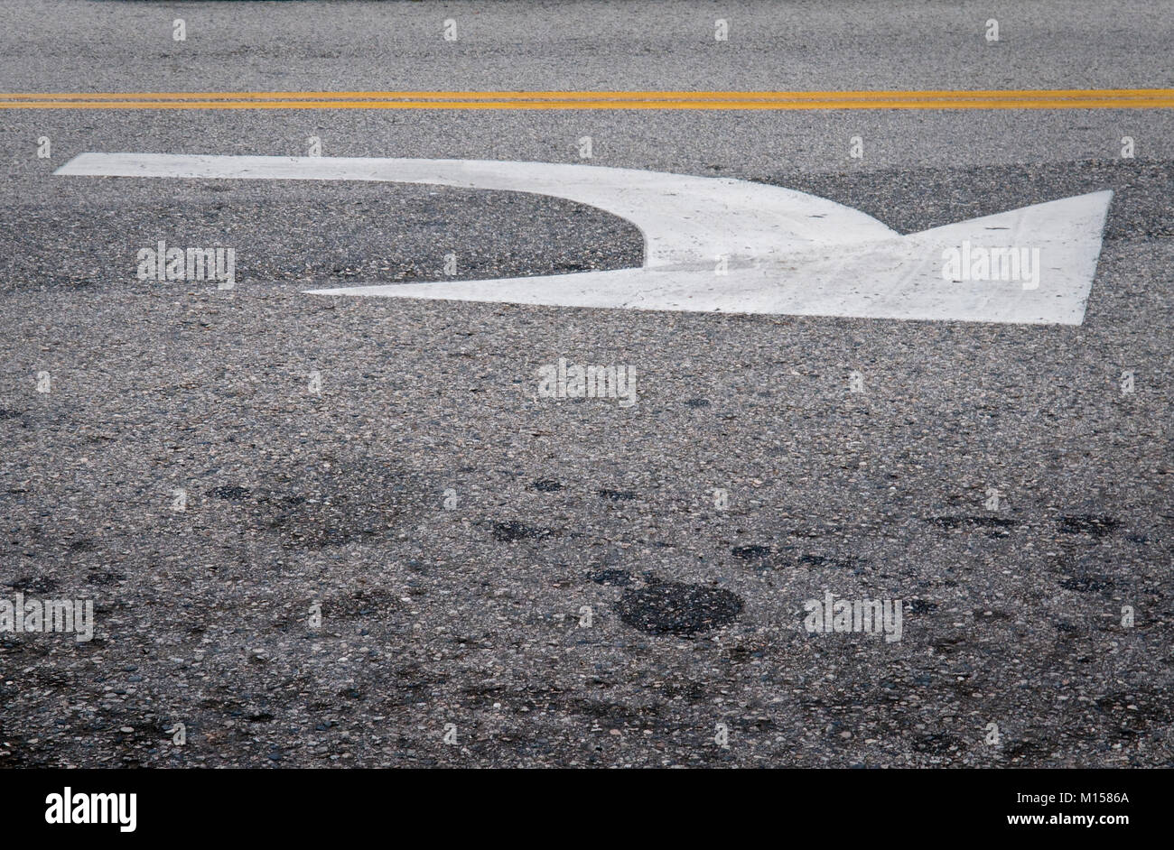 white arrow turning to the right on asphalt street with yellow line ...