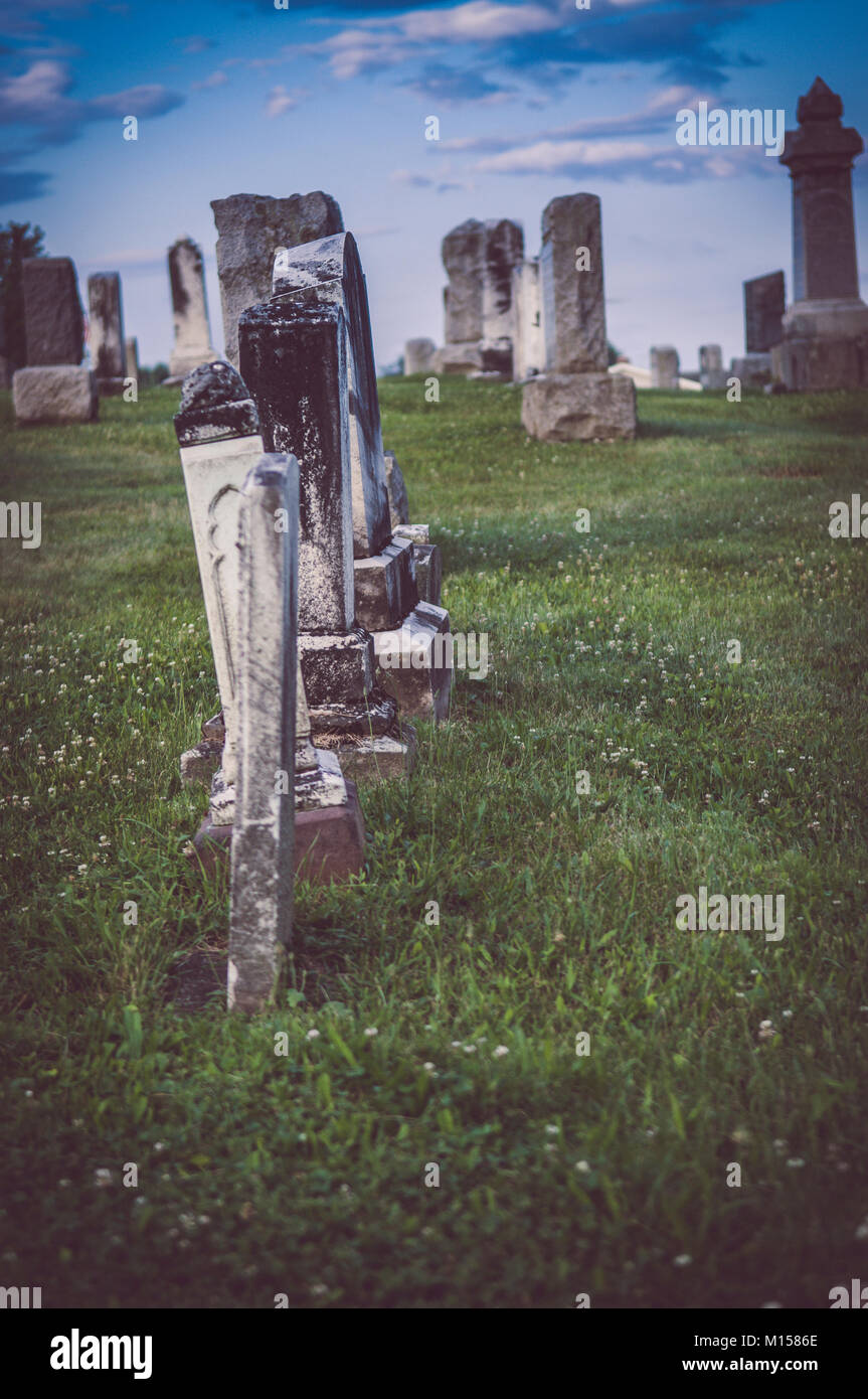 Tilted grave stones in graveyard processed in dark, spooky, moody style ...
