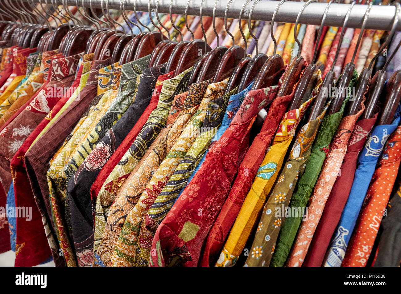 Colorful silk batik shirts on a rack in Hamzah Batik shop. Yogyakarta ...