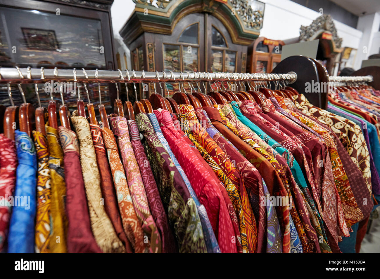 Colorful silk batik shirts on a rack in Hamzah Batik shop. Yogyakarta ...