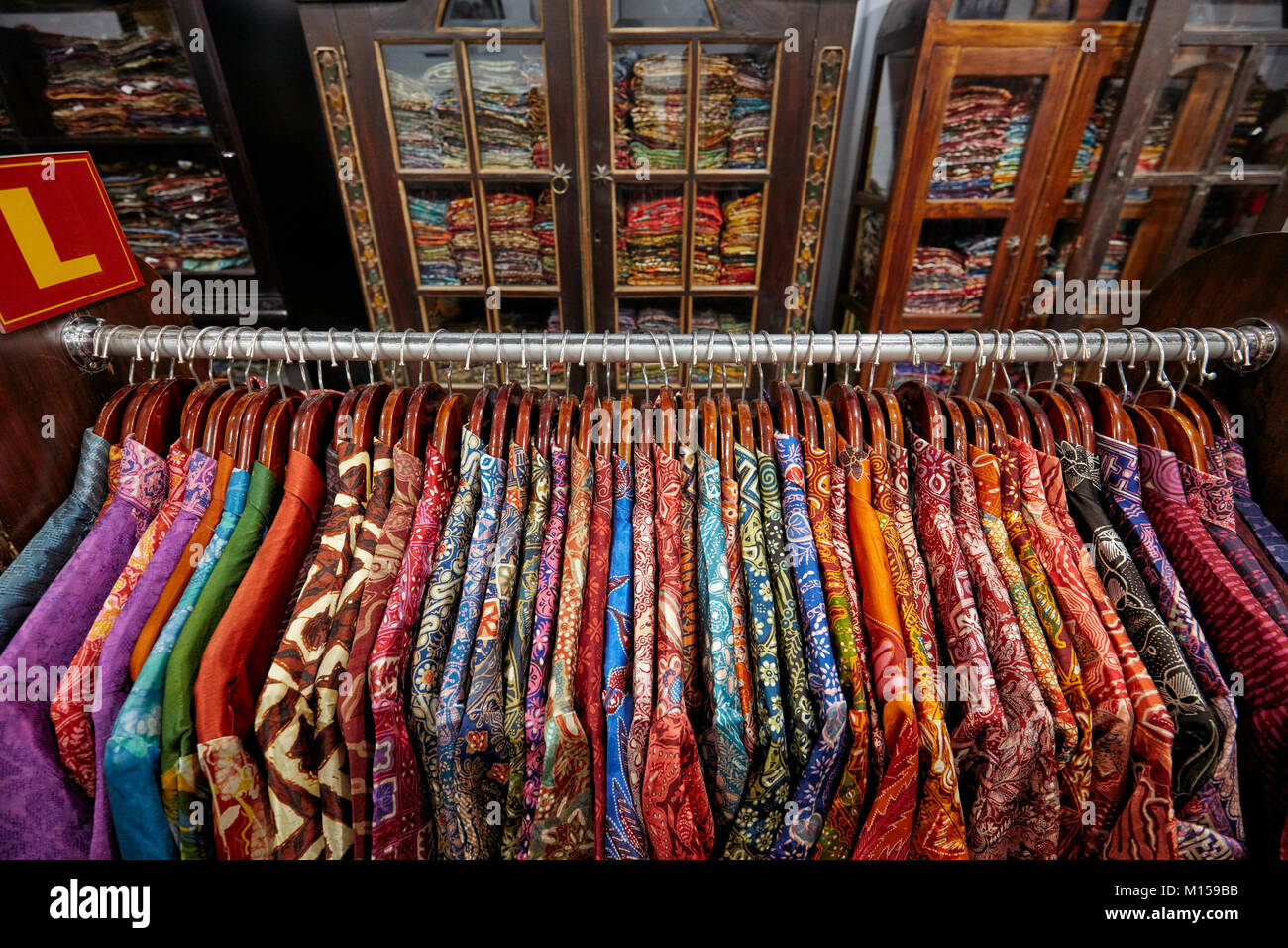 Colorful silk batik shirts on a rack in Hamzah Batik shop. Yogyakarta ...