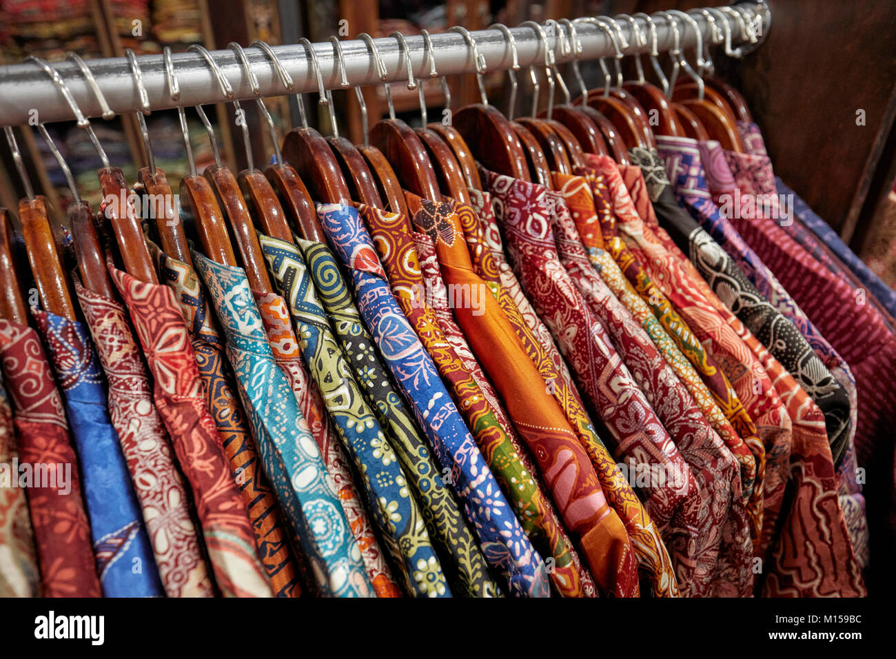Colorful silk batik shirts on a rack in Hamzah Batik shop. Yogyakarta ...