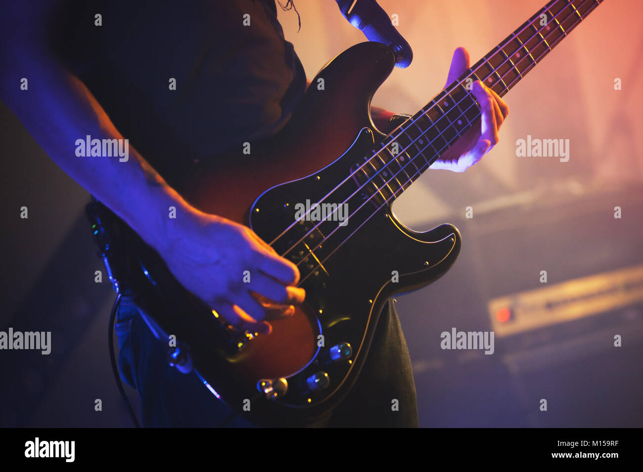 Electric bass guitar player on a stage, closeup photo with soft ...