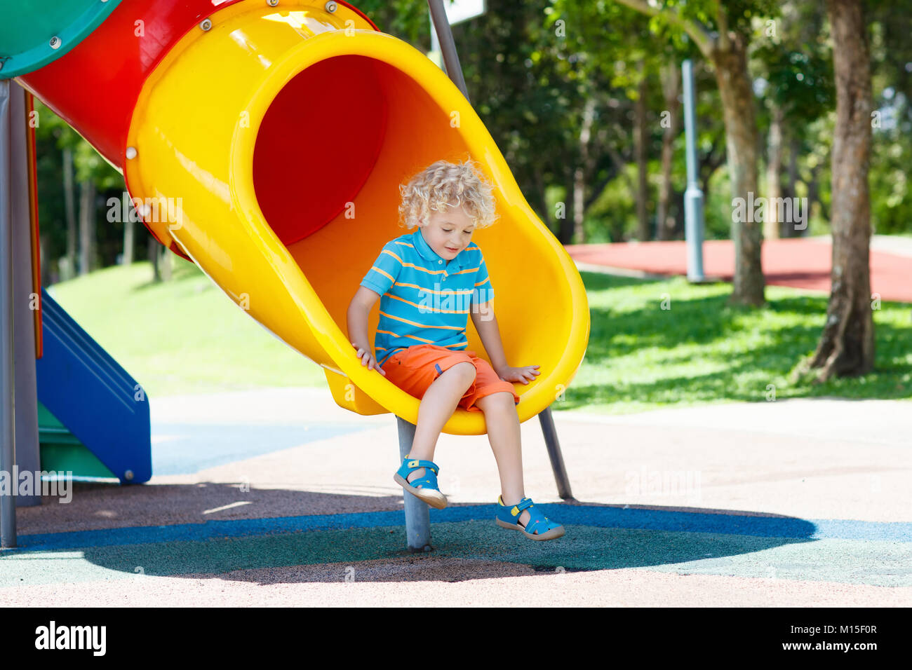 Kids climbing and sliding on outdoor playground. Children play in sunny ...