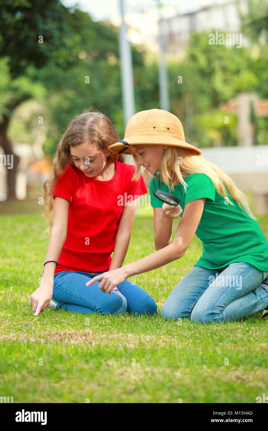 Two school girls exploring the nature with magnifying glass Stock Photo ...