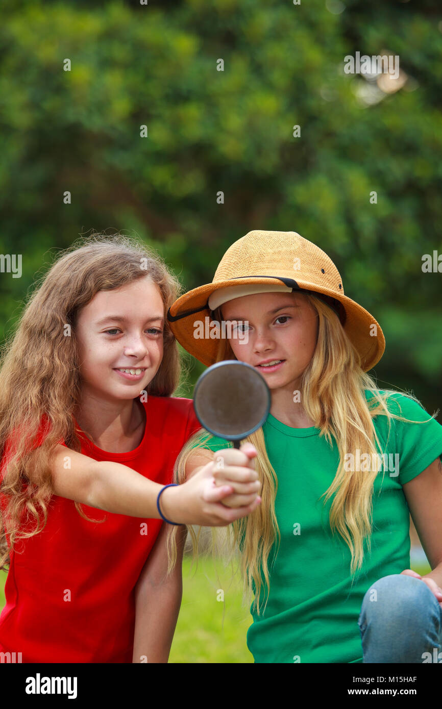 Two school girls exploring the nature with magnifying glass Stock Photo ...