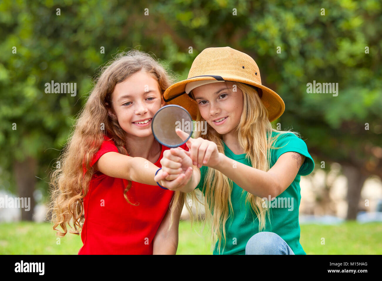 Two school girls exploring the nature with magnifying glass Stock Photo ...