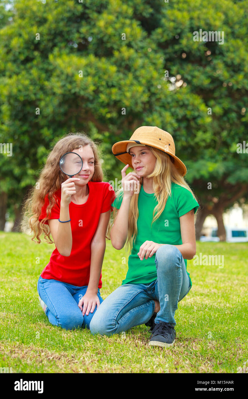 Two school girls exploring the nature with magnifying glass Stock Photo ...