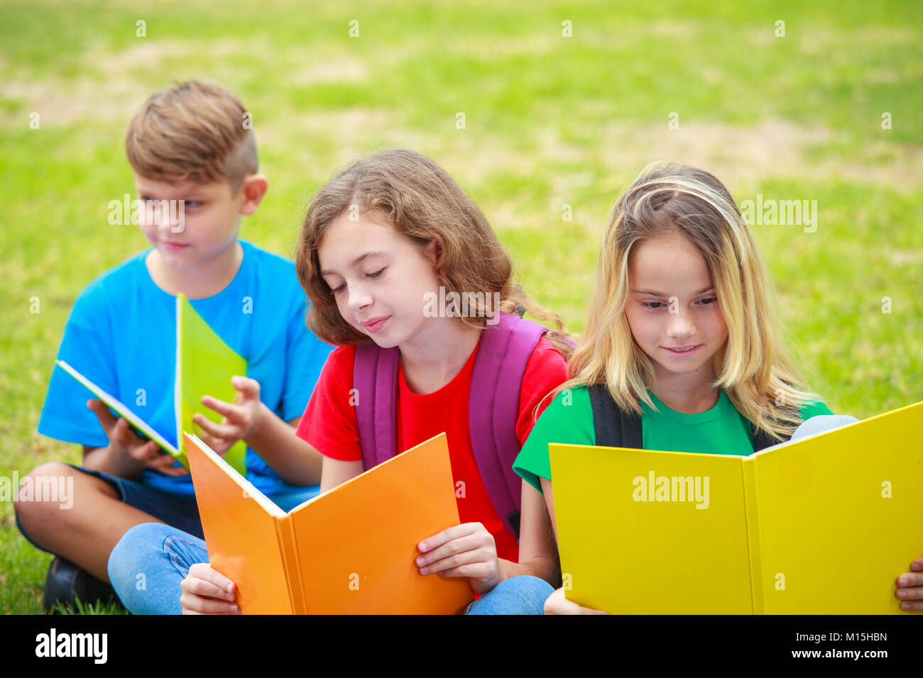Group of children reading books at the park Stock Photo - Alamy