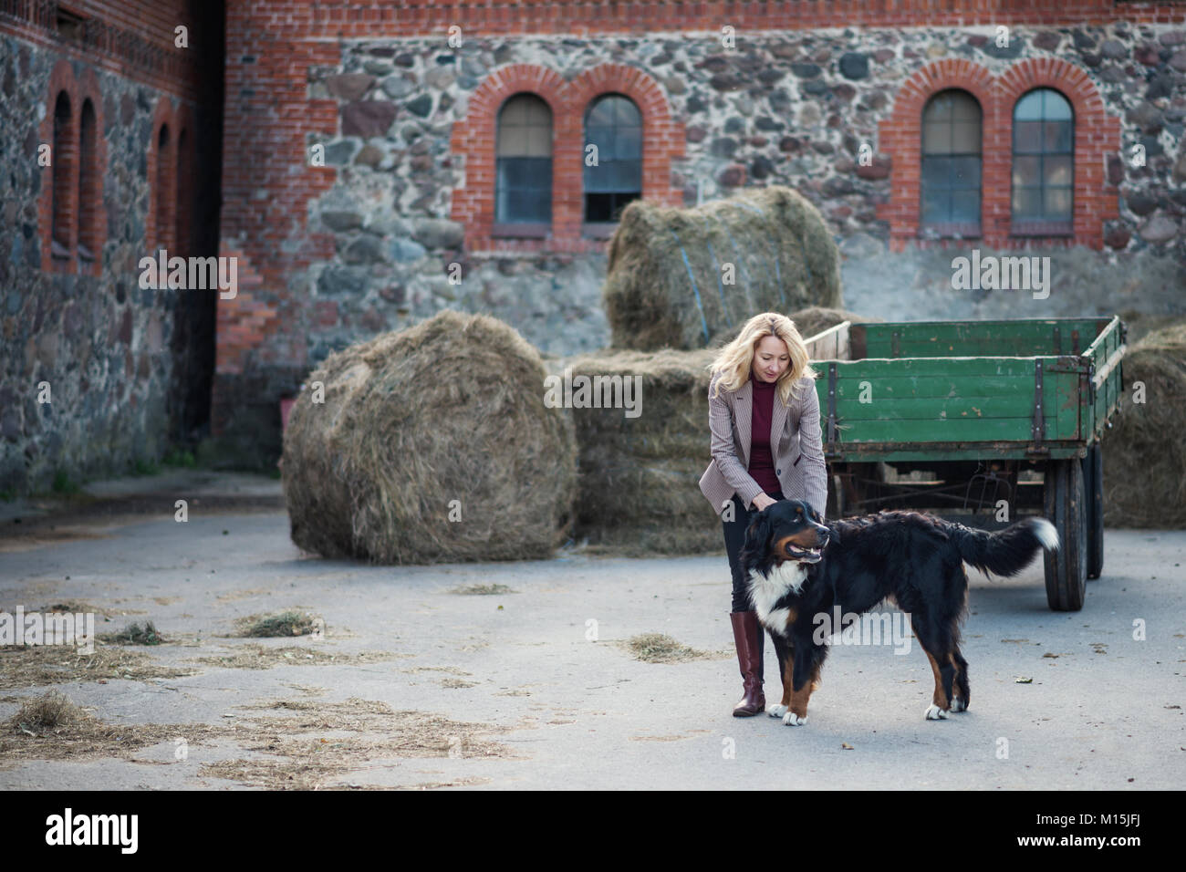 Blond woman is holding a dog on a farm Stock Photo - Alamy