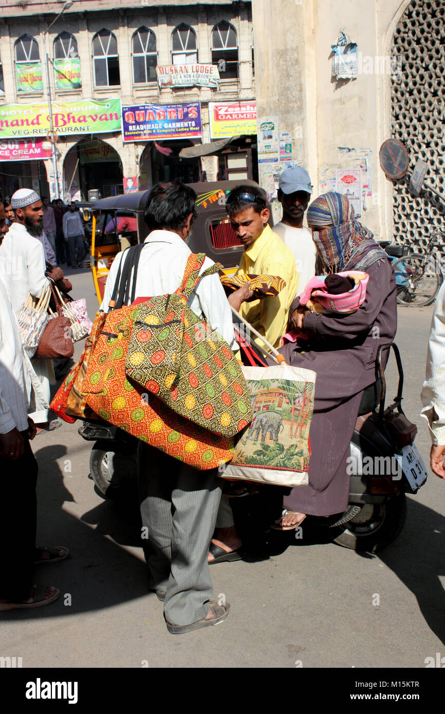 Indian man selling bags to Muslim woman on scooter Stock Photo - Alamy