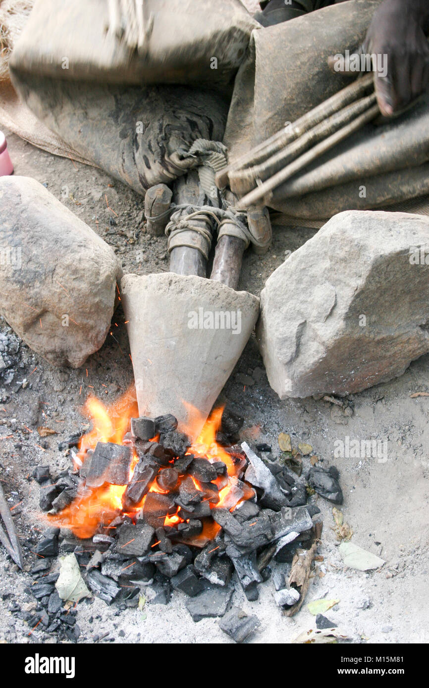 Datoga man prepares and lights the campfire using a goat skin bellows ...