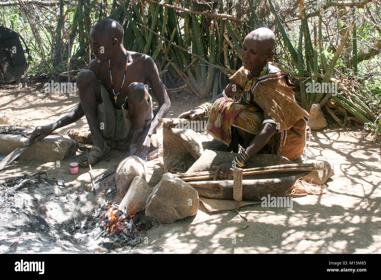 Datoga man prepares and lights the campfire using a goat skin bellows ...