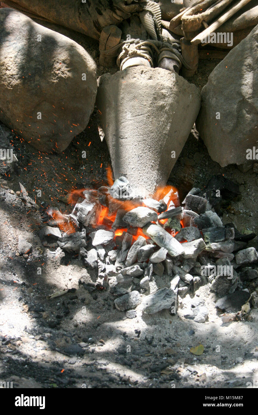 Datoga man prepares and lights the campfire using a goat skin bellows ...