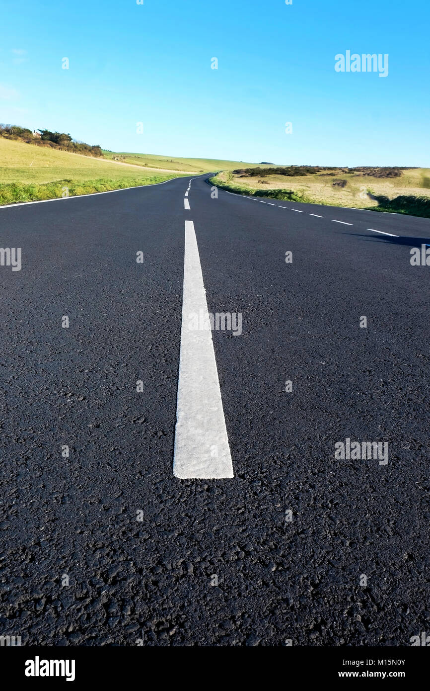 A camber on grey asphalt country road with strong white lines in the ...