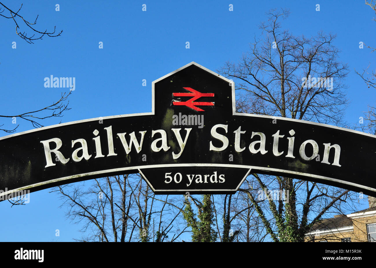 Railway station sign with distance information over city walkway ...