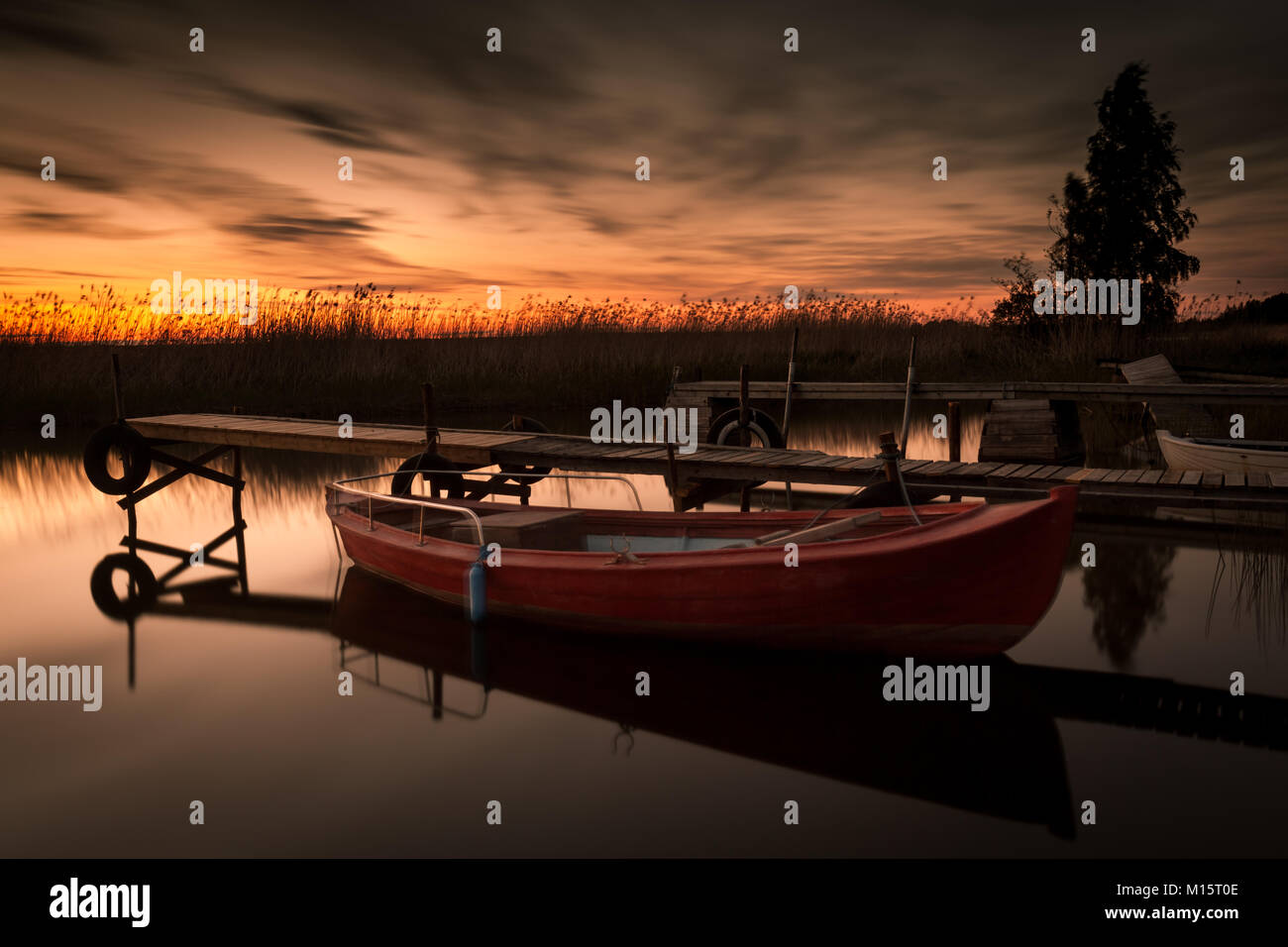 Red rowboat in calm sunset Stock Photo - Alamy