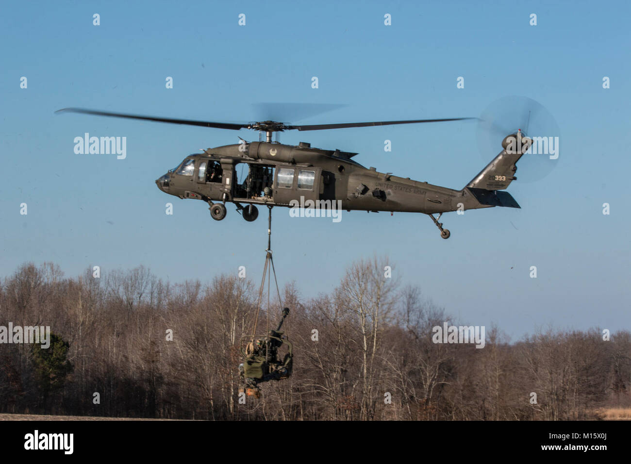 A UH-60 Black Hawk sling loads a Howitzer M119A3 to the firing point ...