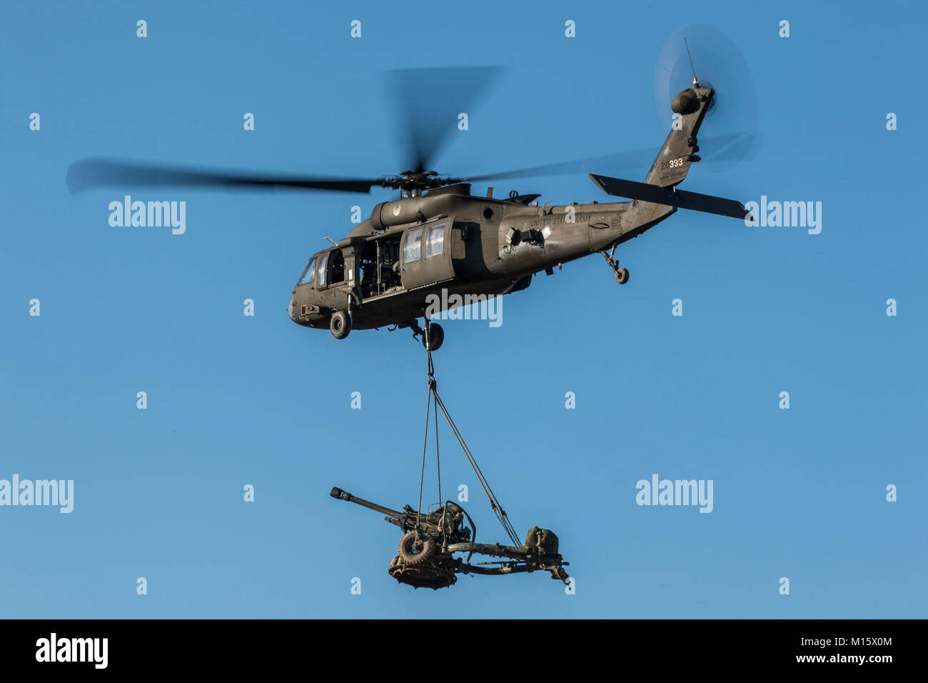 A UH-60 Black Hawk sling loads a Howitzer M119A3 to the firing point ...