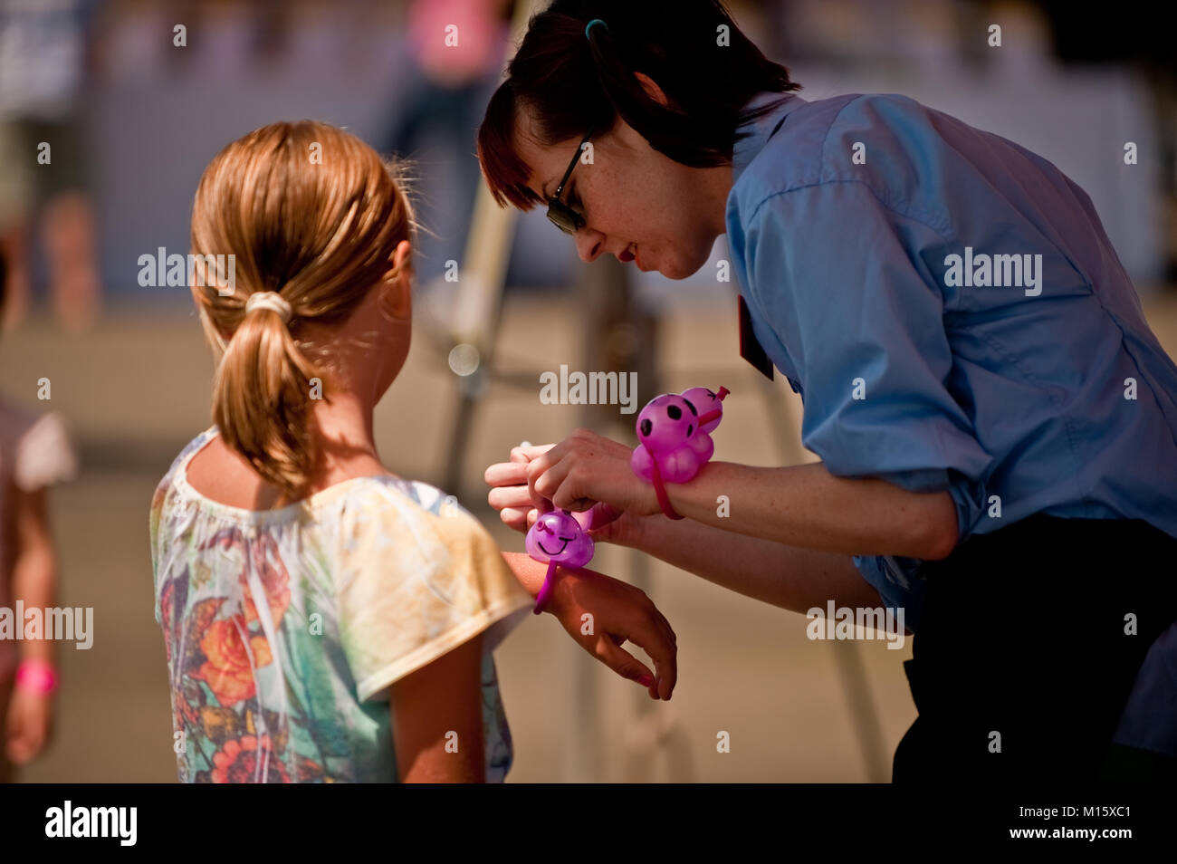 A female balloon artist handing out balloon animal to little kid Stock ...