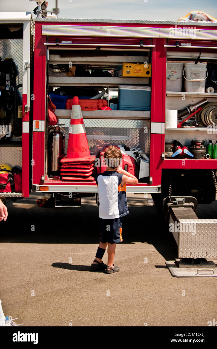 A boy looking at fire fighting equipment on display inside a fire truck ...