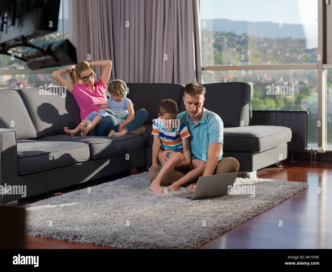 young happy family relaxing at home using laptop and tablet computers ...