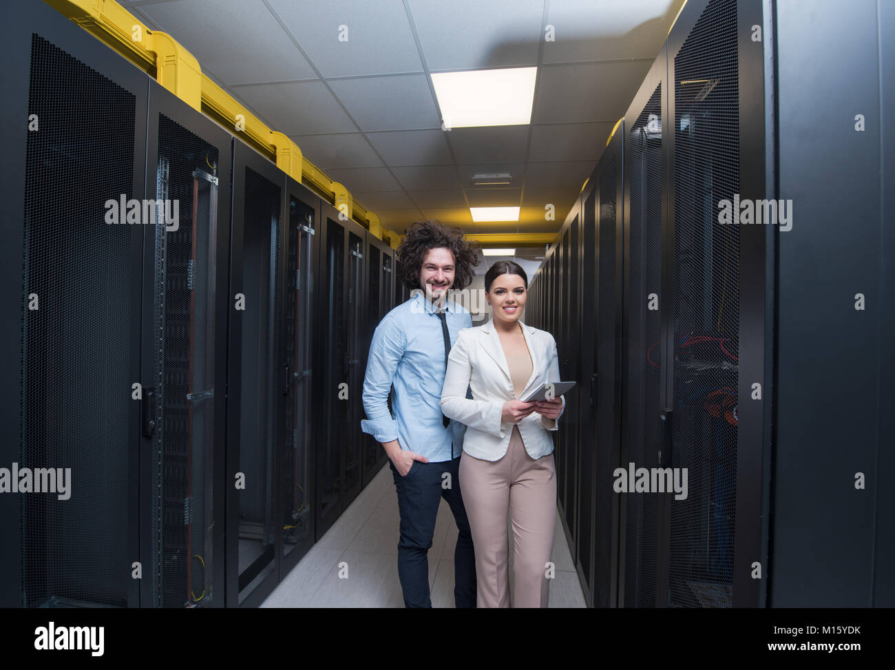 Young IT engineer showing working data center server room to female ...