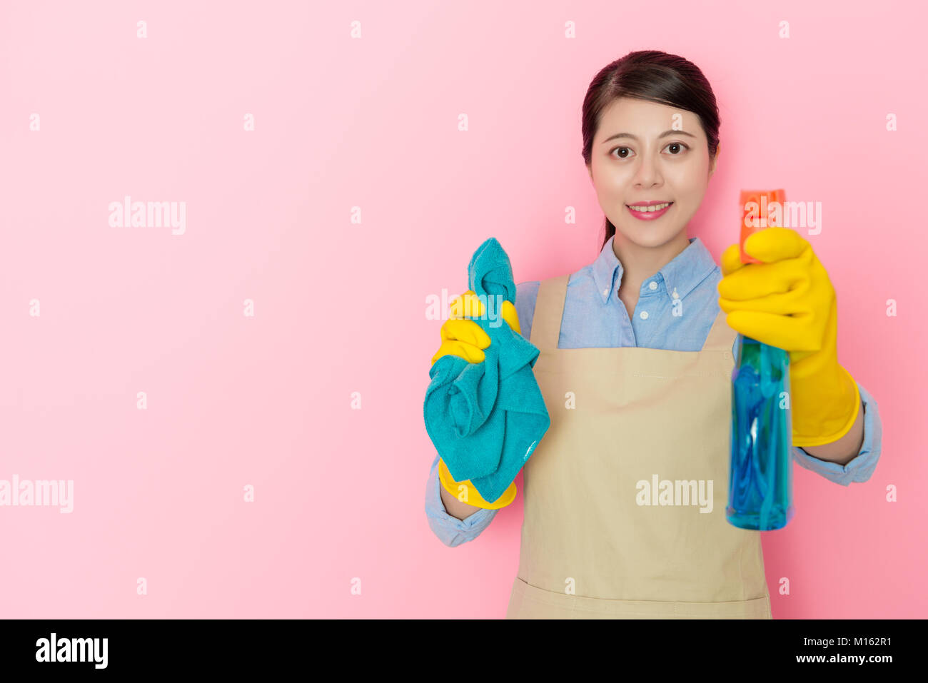 beautiful pretty woman housekeeper looking at camera spraying detergent ...