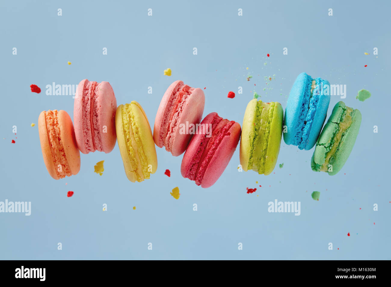Different types of macaroons in motion falling on blue background ...