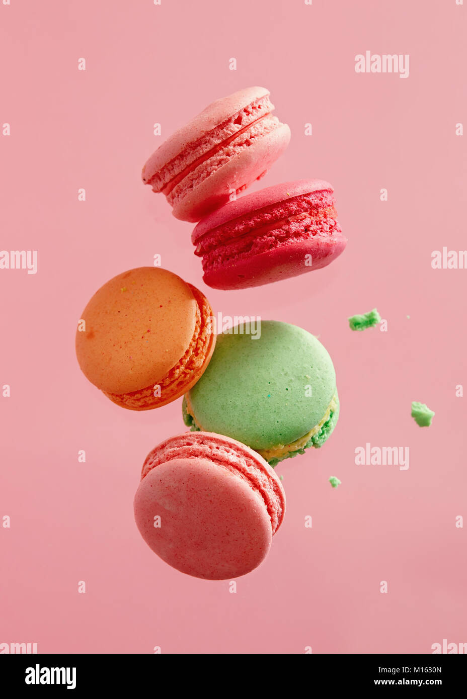 Different types of macaroons in motion falling on pink background ...