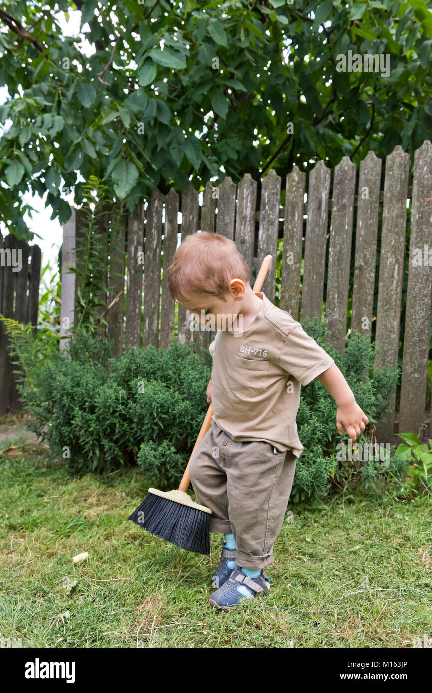 Blonde child with blue eyes, playing with a broom, outdoor, portraits ...