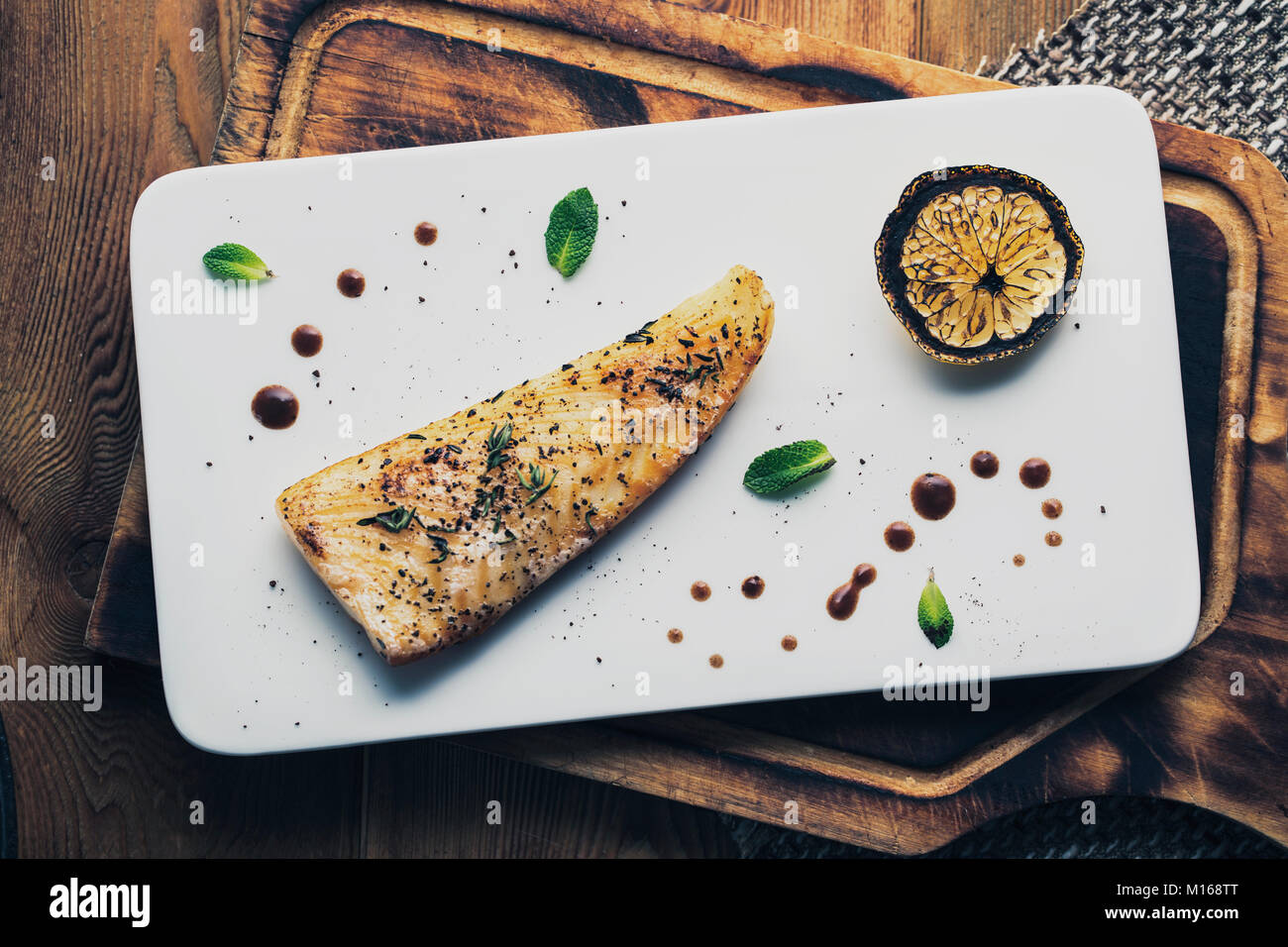 Steak of sea fish halibut with lemon on the grill. Rustic style. Toning ...