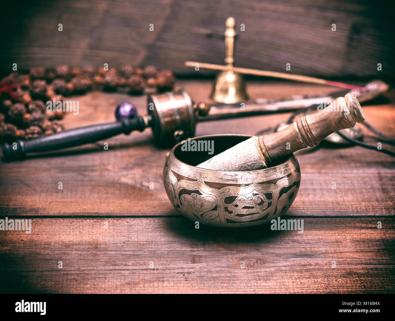 copper singing bowl and a wooden stick on a brown table, a vintage ...