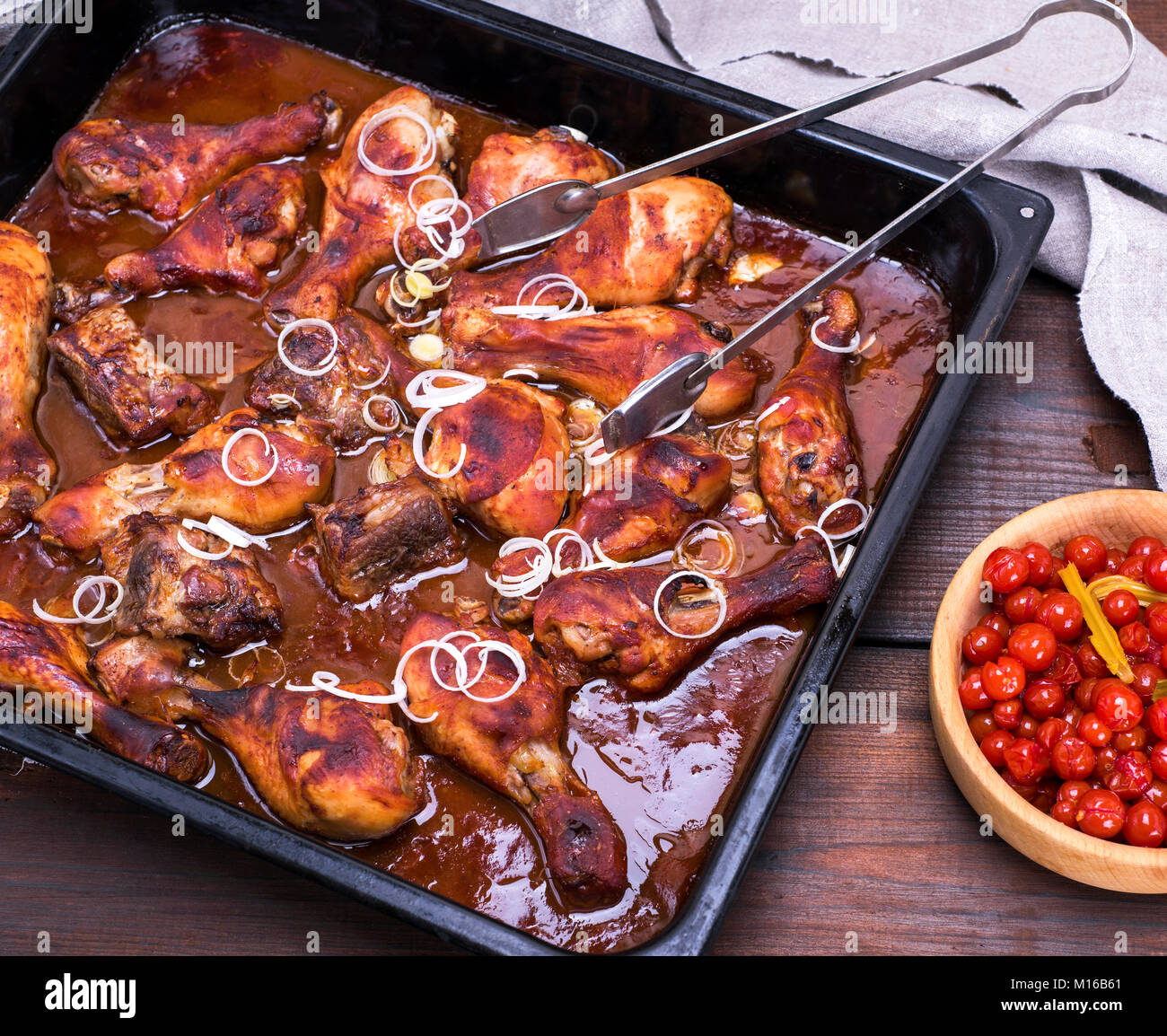 fried chicken legs with crispy crust in honey tomato sauce on a black ...