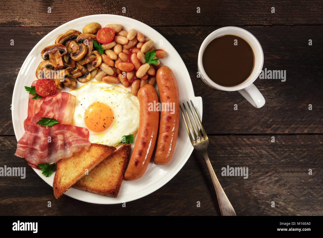 An overhead photo of a plate of full breakfast on a dark rustic texture ...