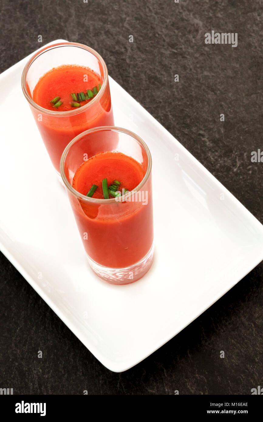 Spanish tapas in a modern bar. Two shots of gazpacho, cold tomato soup ...