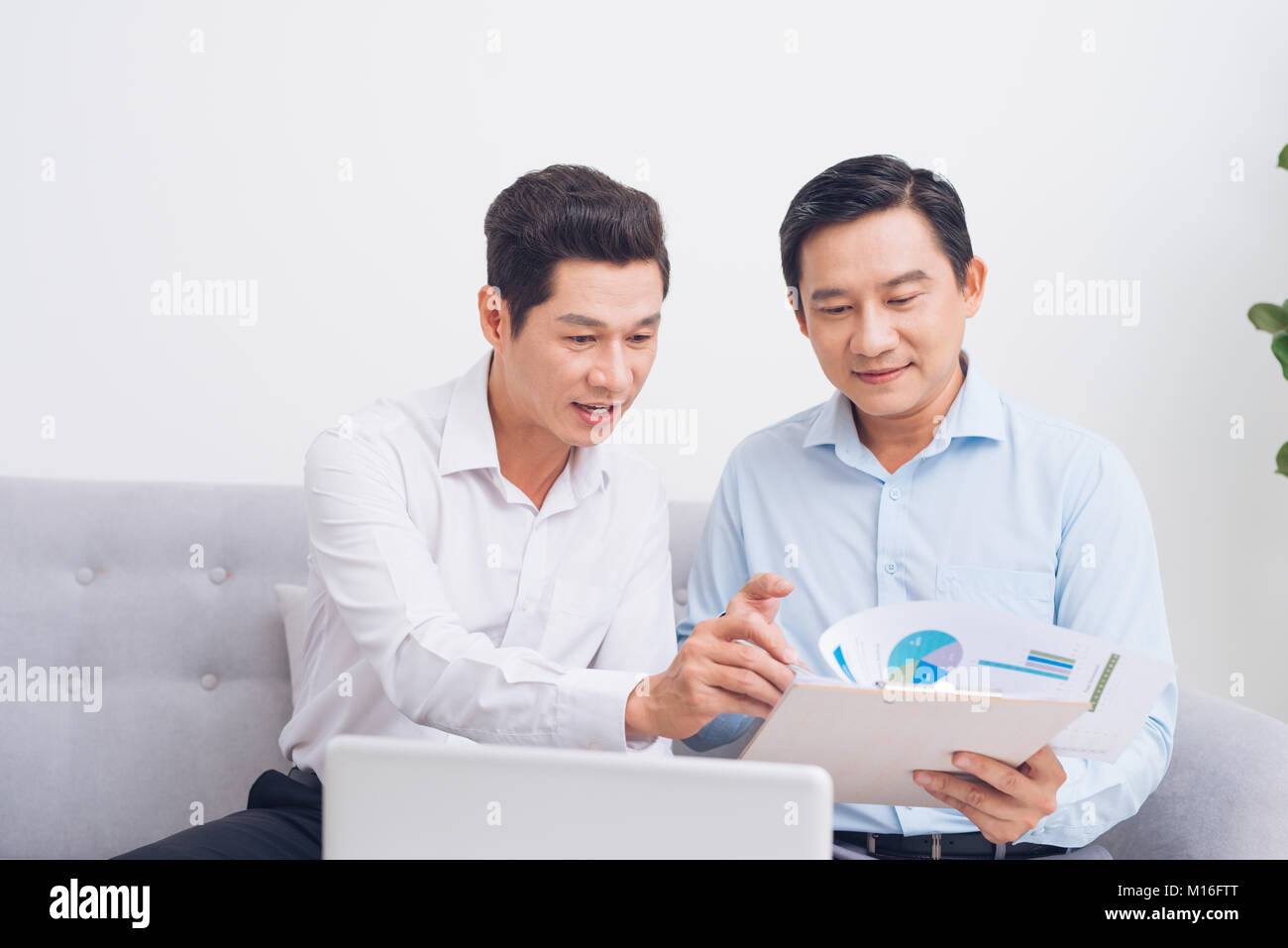 Two confident young businesspeople using a laptop discuss information ...