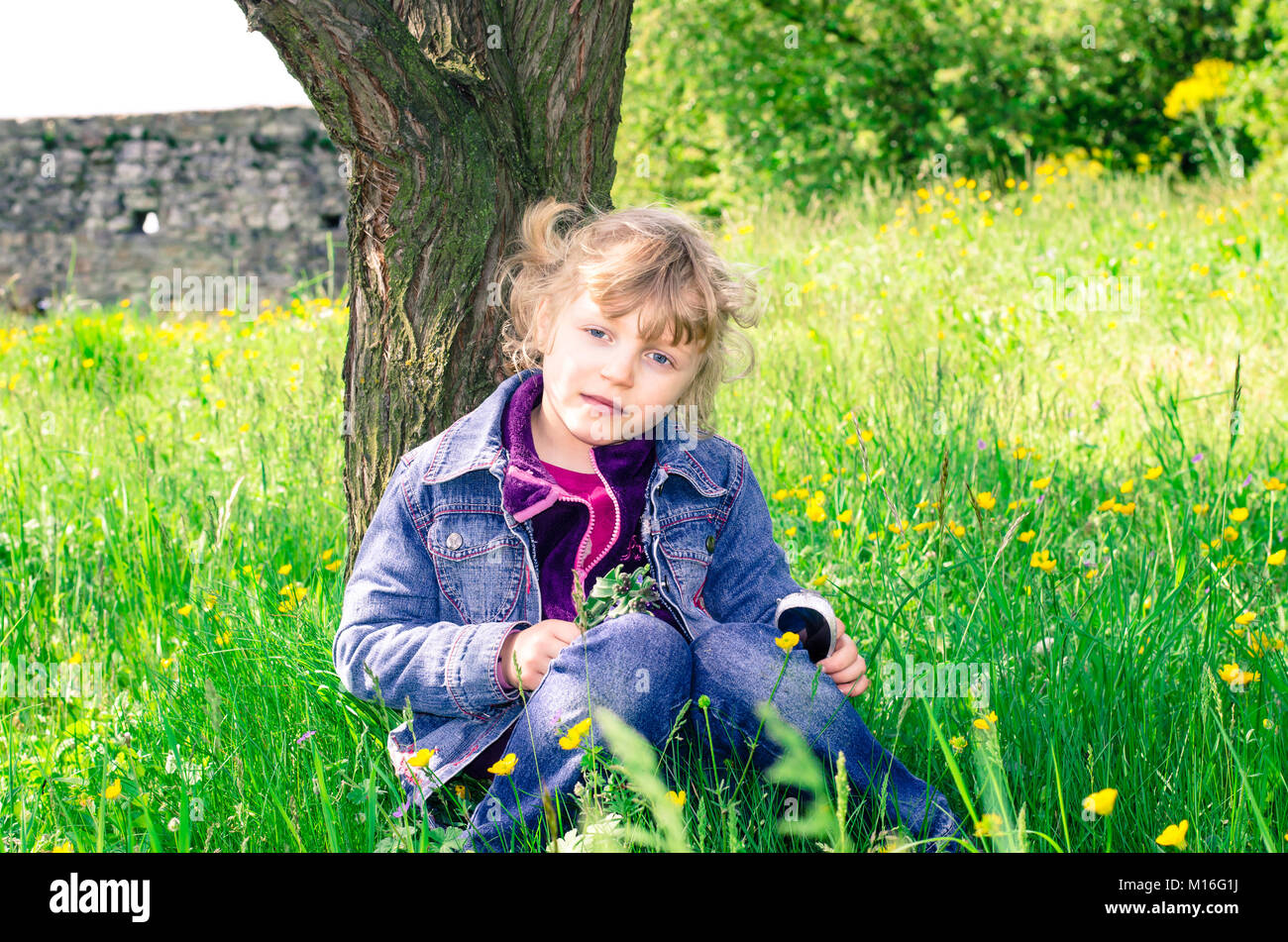 blond girl sitting next to the tree Stock Photo - Alamy