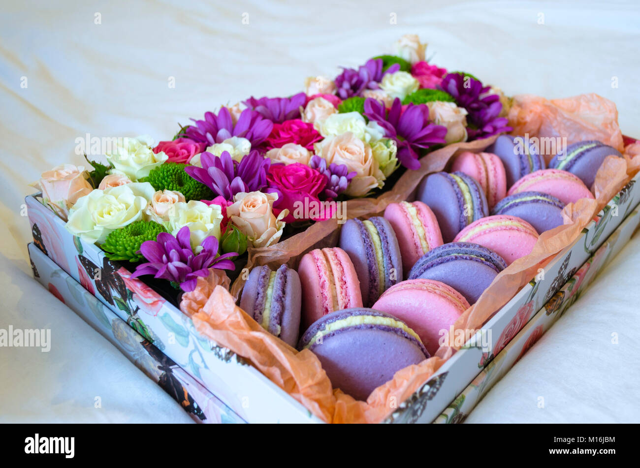 French macaroon cake. Violet and pink macaroons in a box with flowers ...