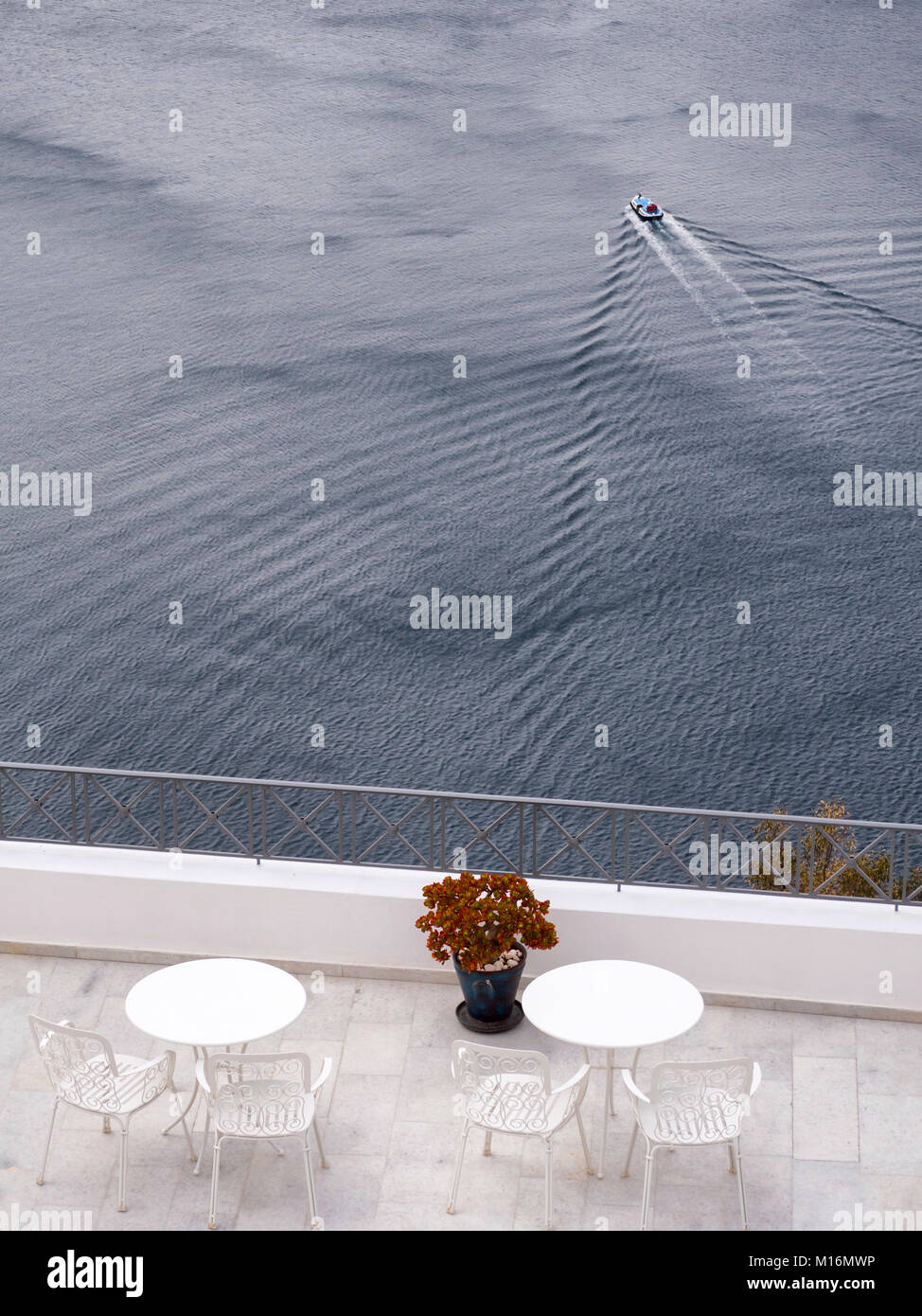 Balcony with tables and sea view with a boat passing in the background ...