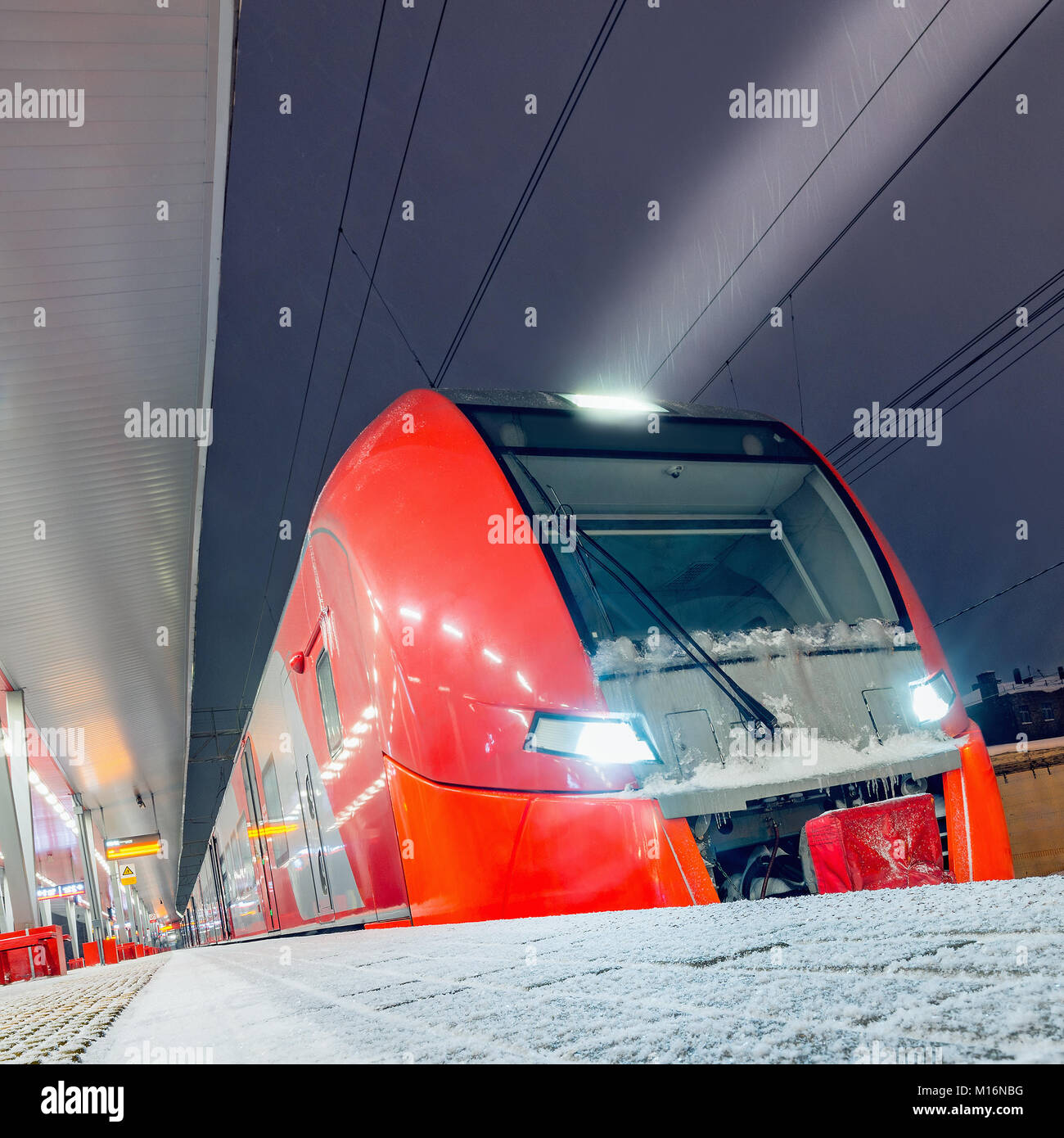 Highspeed train stands at the station platform at winter evening time ...