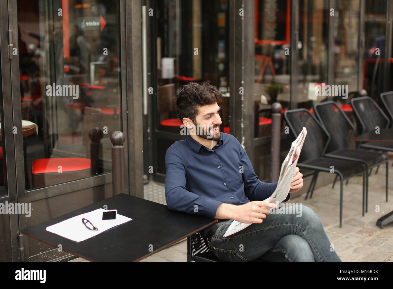Journalist with close up face reading newspaper article at cafe Stock ...