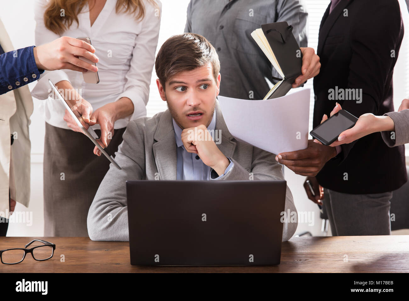 Scared Young Businessman Surrounded By Hands That Give Him A Lot Of ...
