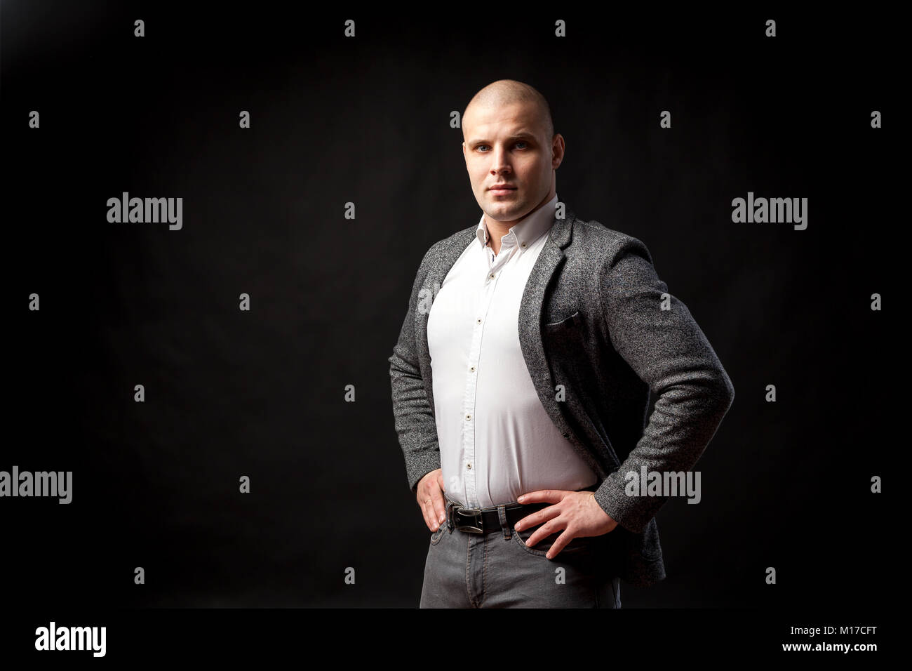 A bald man businessman in a white shirt, gray suit stands in a ...