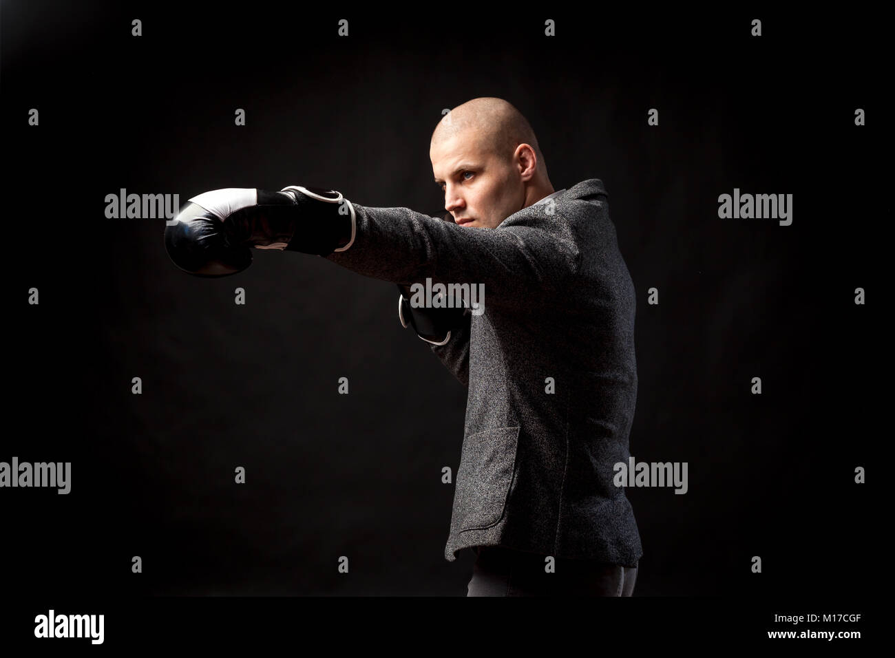 A bald man manager in a white shirt, gray suit, boxing gloves boxing on ...