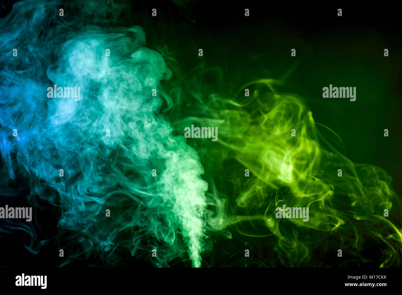 Dense multicolored smoke of green and blue colors on a black isolated ...