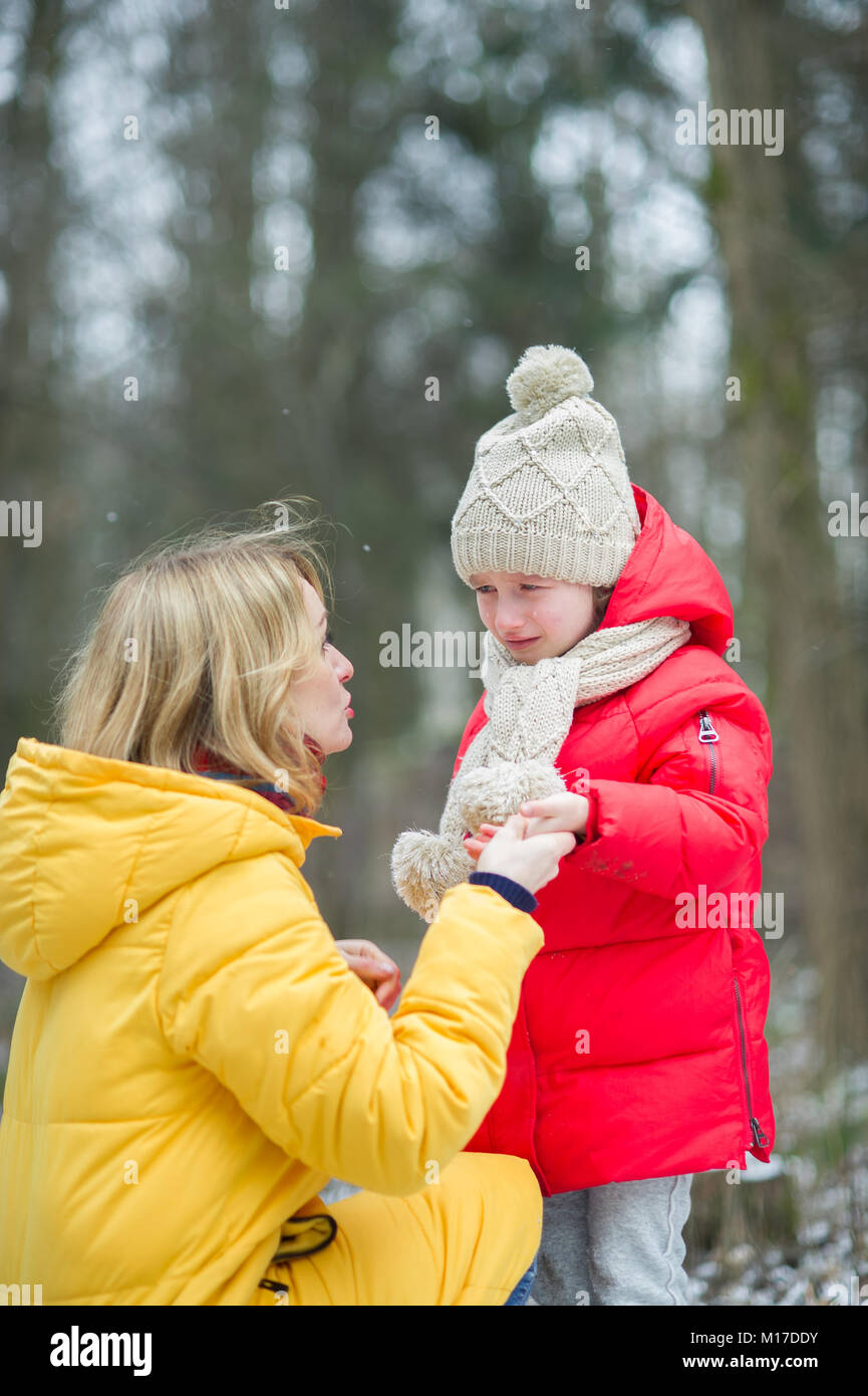 Young mother consoles the crying child. The girl has fallen during walk ...